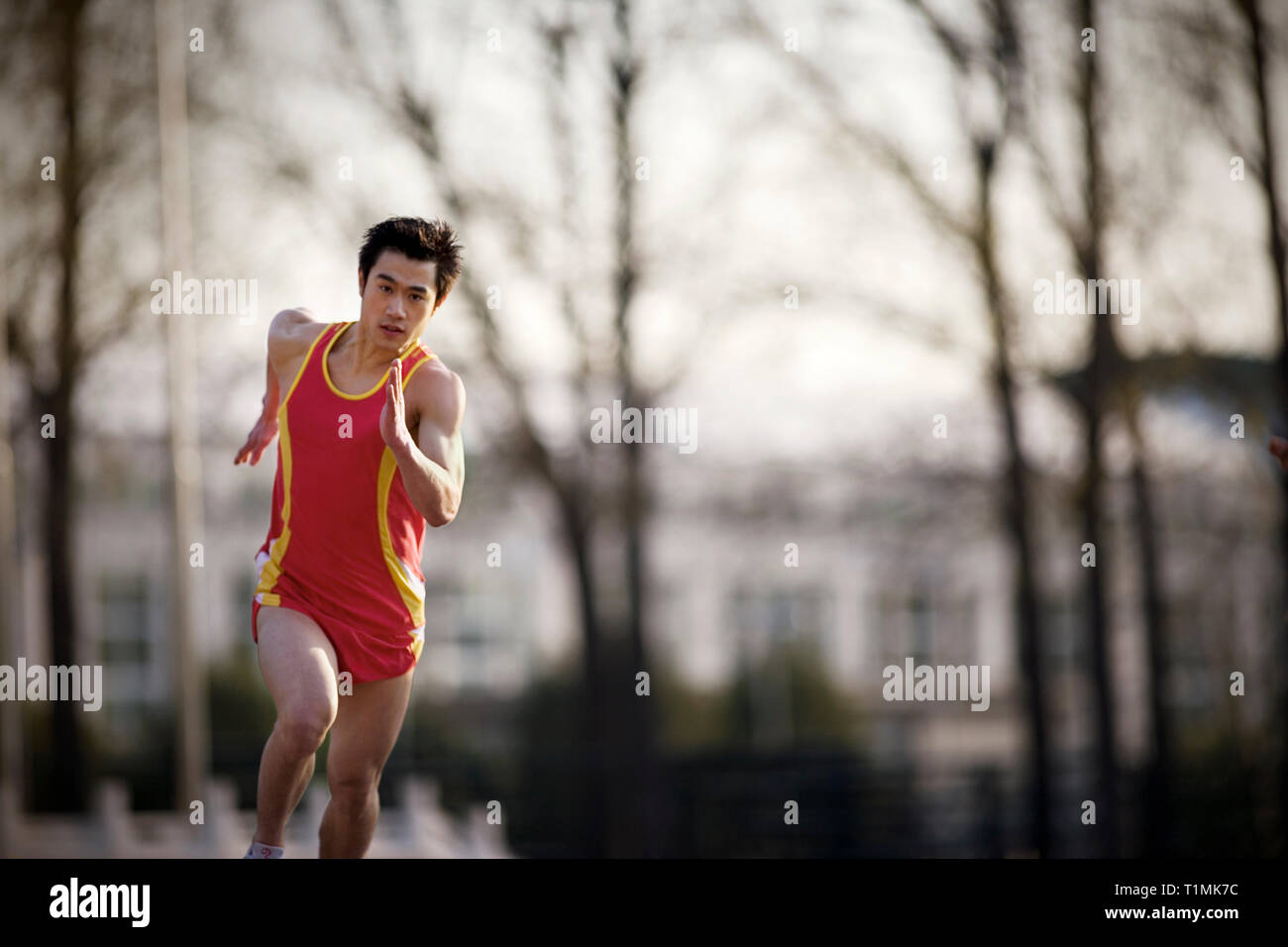 Young adult man running around a track Stock Photo - Alamy