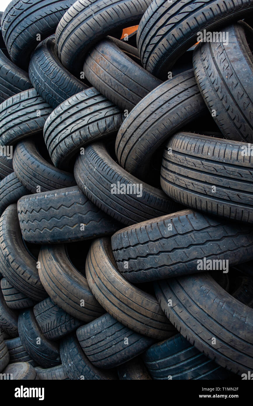 Interesting shapes of used car tyres stacked in a herringbone pattern ...