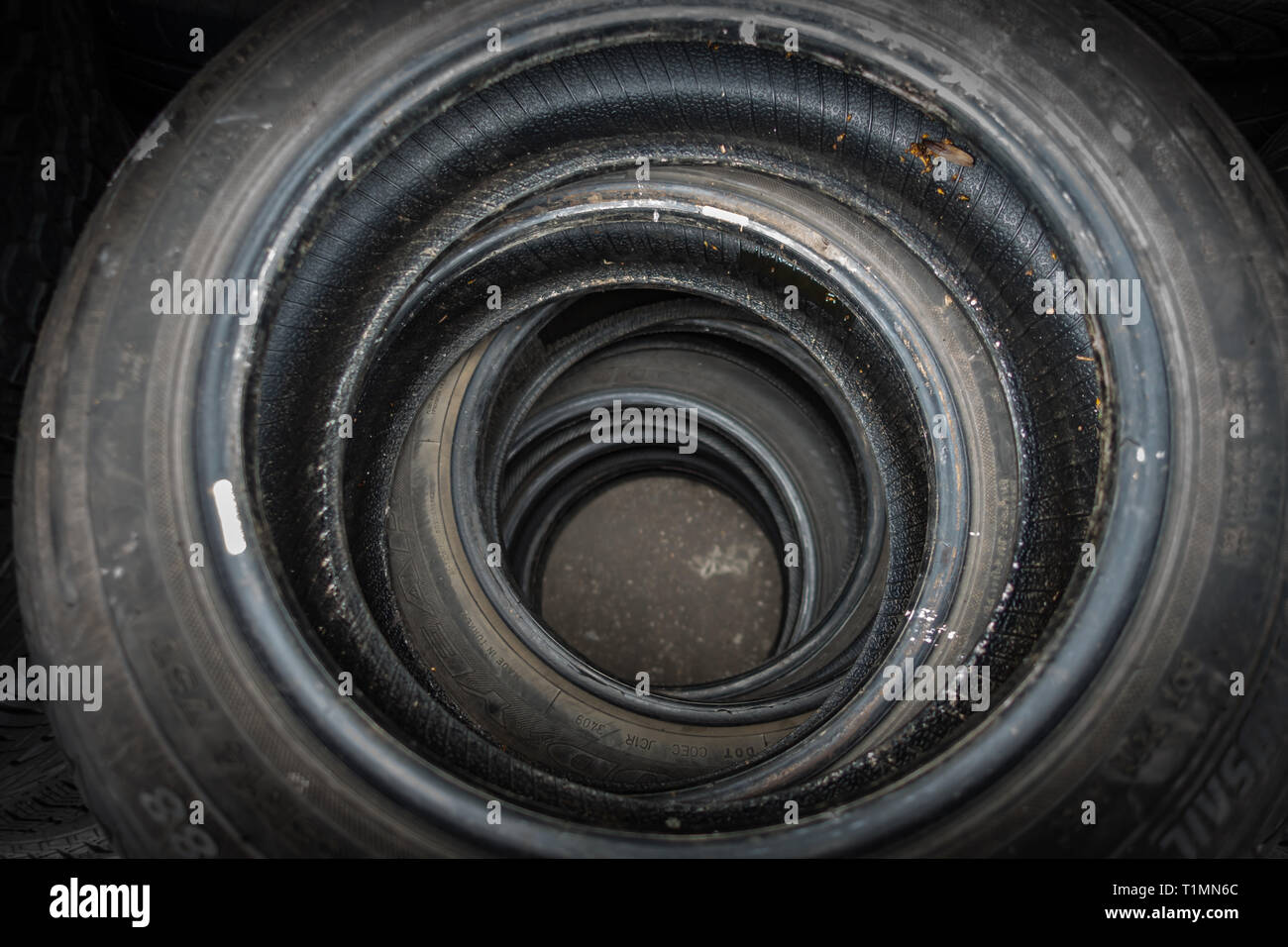 Looking down into the inside of a few used car tyres stacked in a ...
