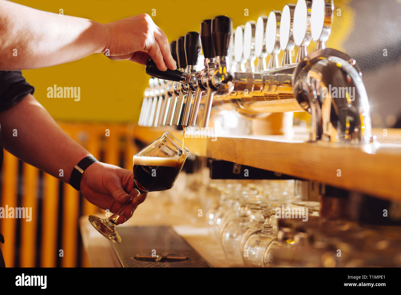 Barman wearing hand watch pouring beer into the glass Stock Photo - Alamy