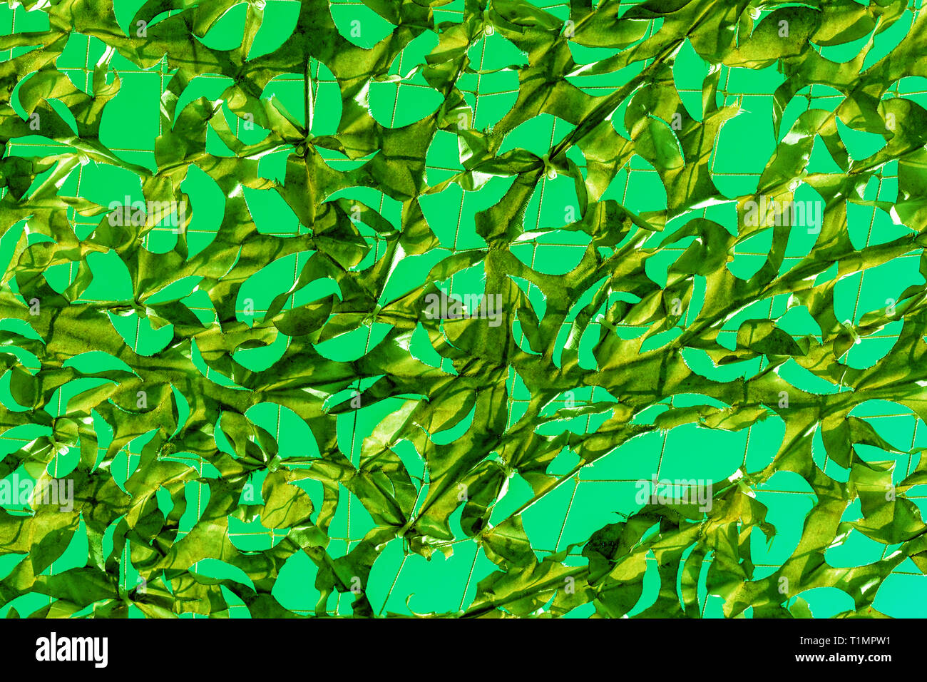 Green military mesh with torn holes with shadows from bright sunlight ...
