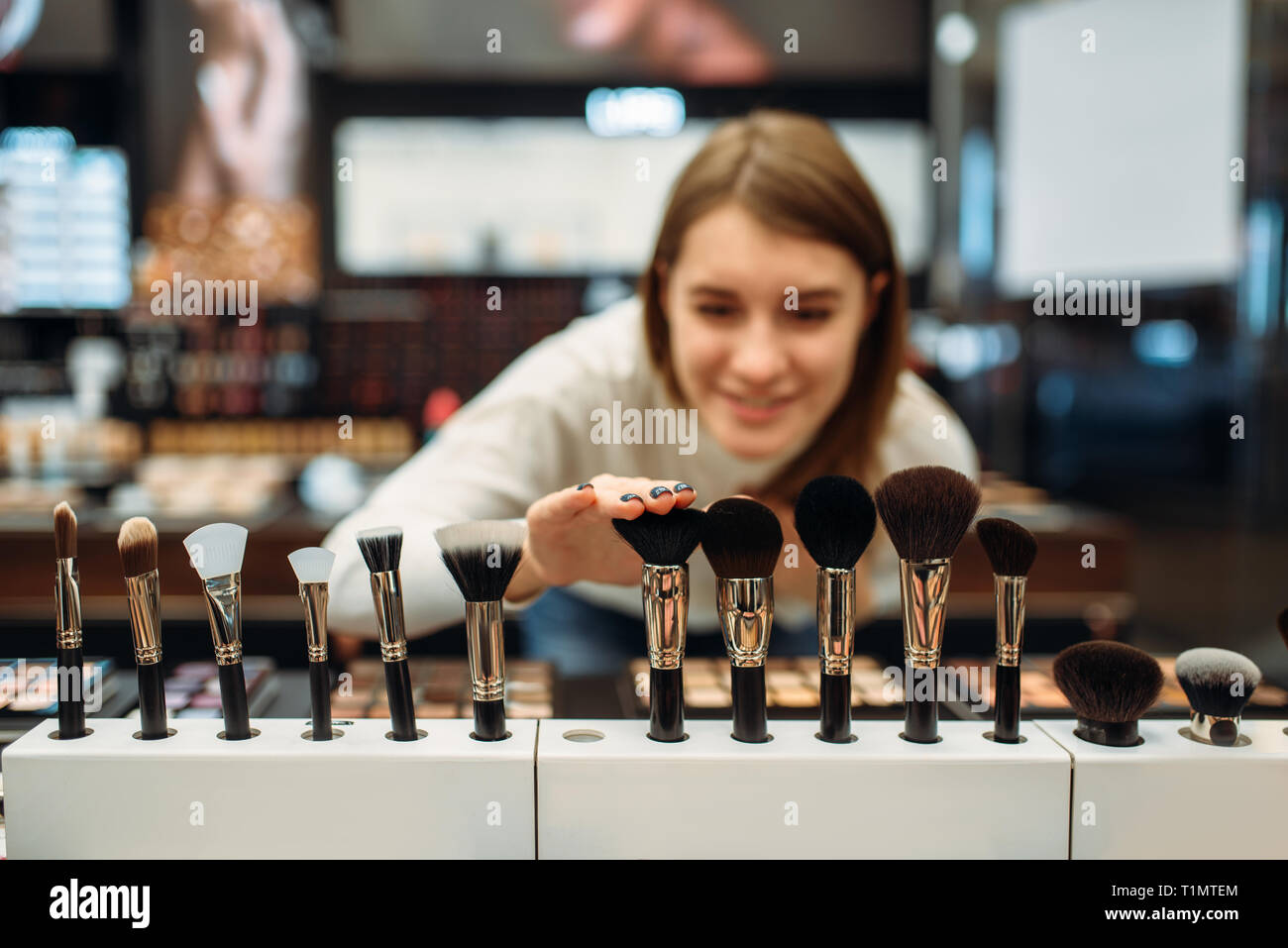 Female customer choosing brushes in makeup shop Stock Photo - Alamy