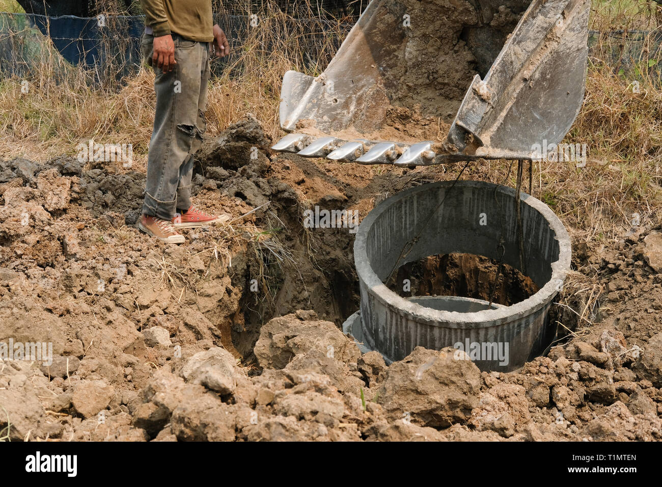 excavator backhoe tractor burying pipe on ground at construction site ...