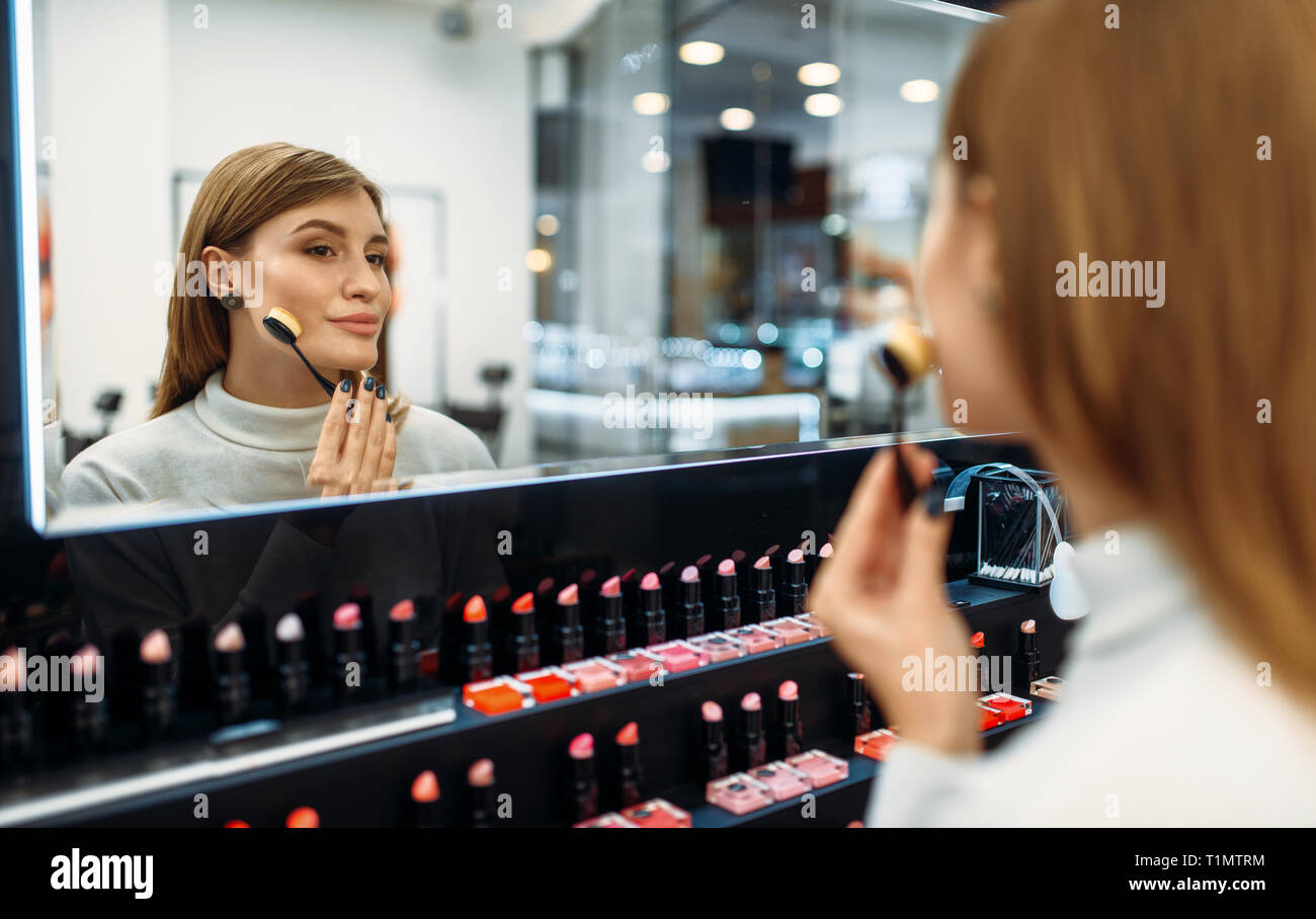 Female customer looks at the mirror in makeup shop Stock Photo - Alamy