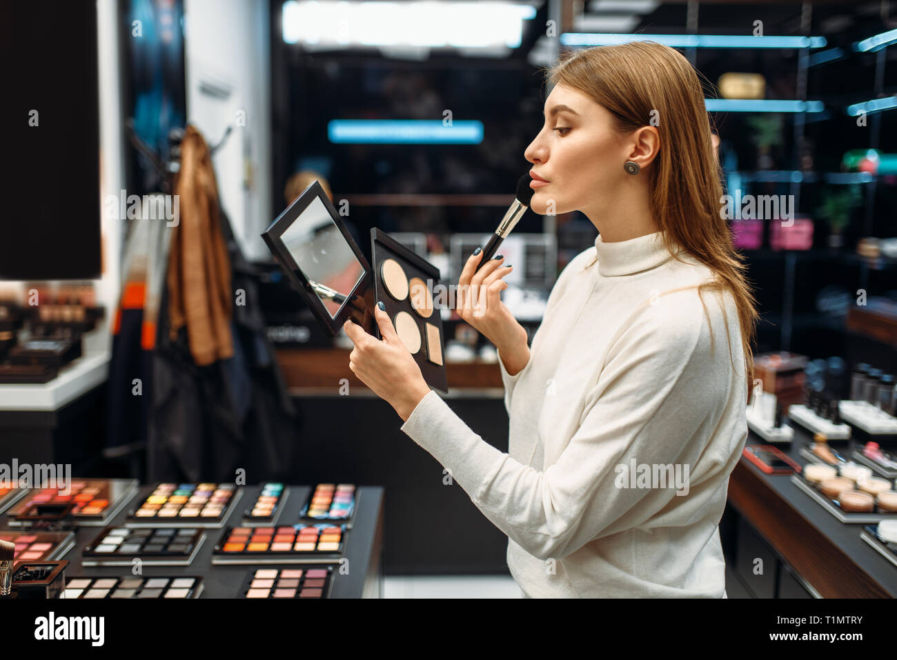 Female customer looks at the mirror in makeup shop Stock Photo - Alamy
