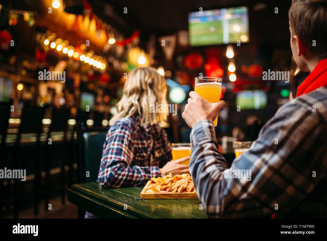 Fans watching match and drinks beer in sports bar Stock Photo - Alamy