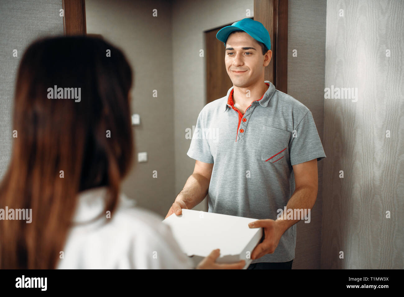 Female customer signs order to pizza delivery boy Stock Photo - Alamy