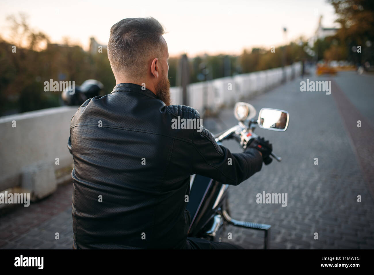 Biker poses on chopper in city, front view Stock Photo - Alamy