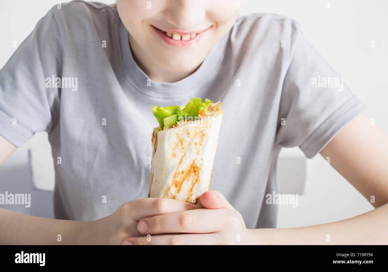Teen boy eating junk food shawarma close-up. Selective focus on ...