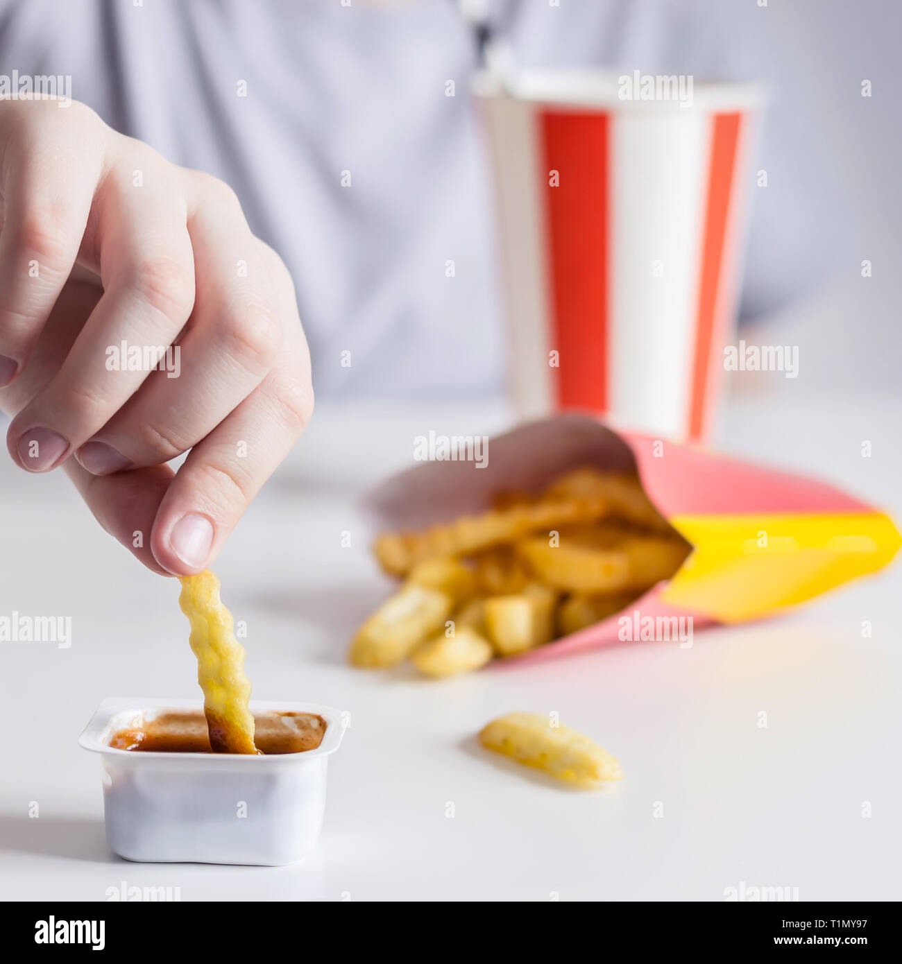 Children's hand dunks french fries in sauce close-up, selective focus ...