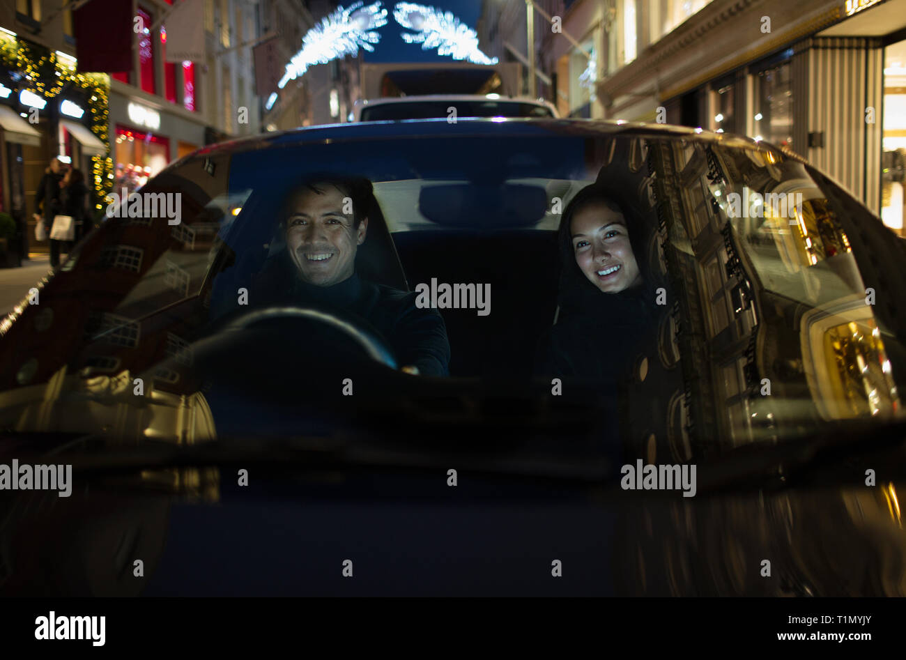 Smiling couple driving car at night Stock Photo - Alamy