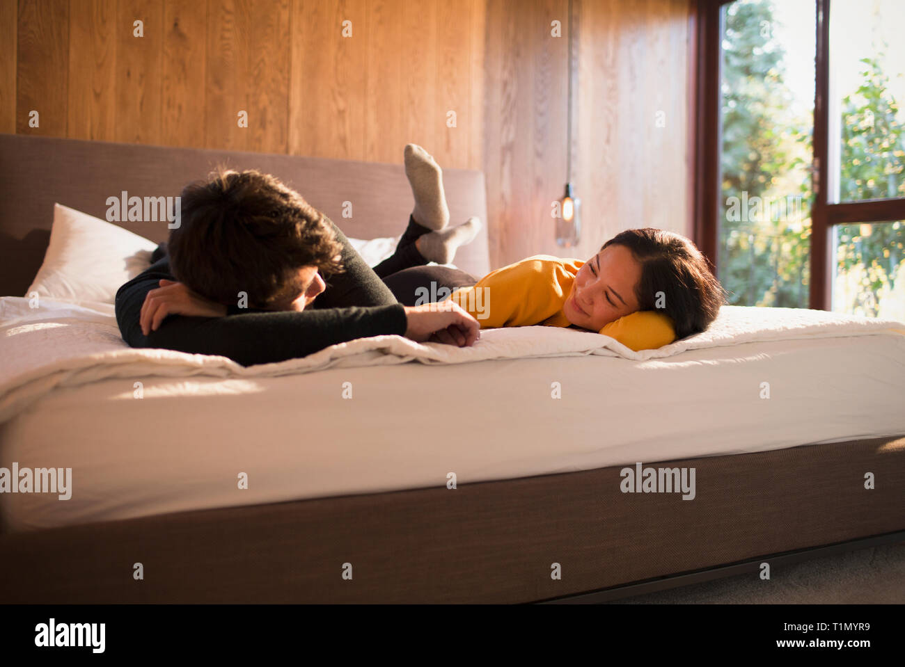 Couple laying on bed talking Stock Photo - Alamy