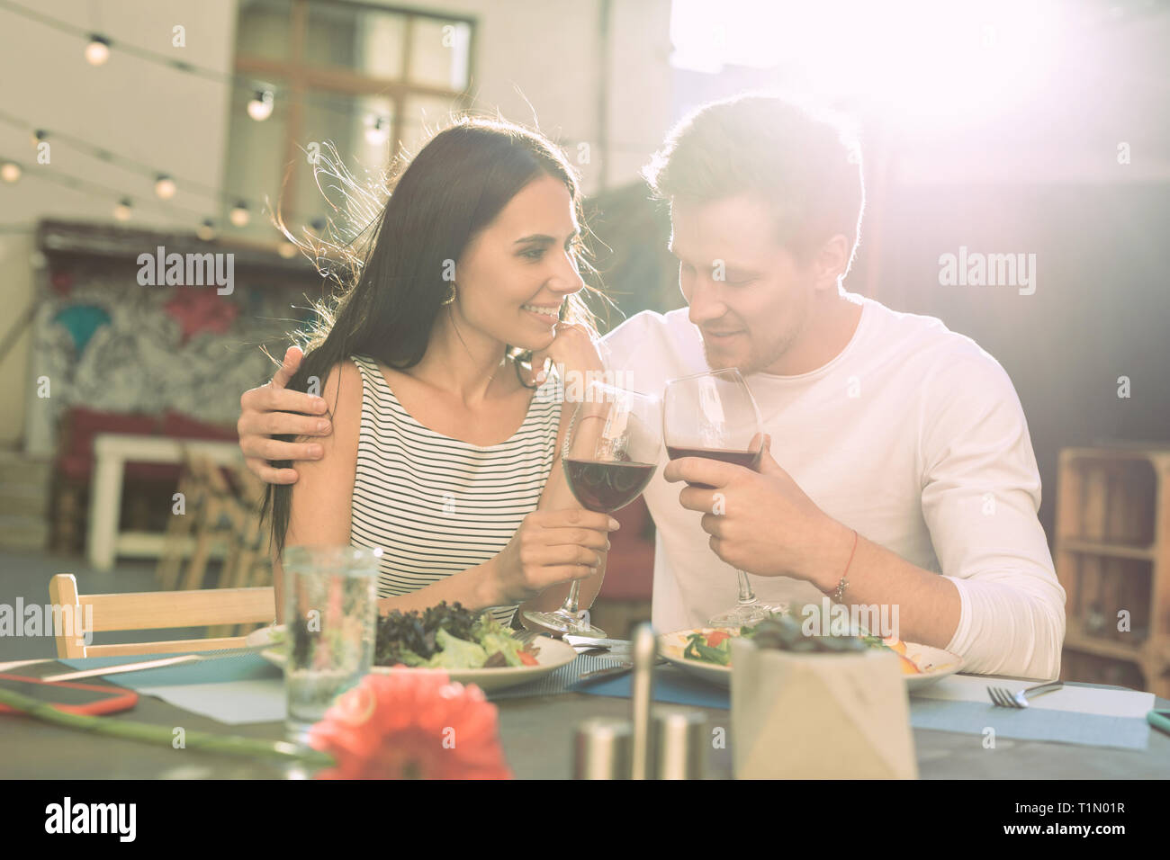 Good-looking young partners sitting close to each other and drinking ...
