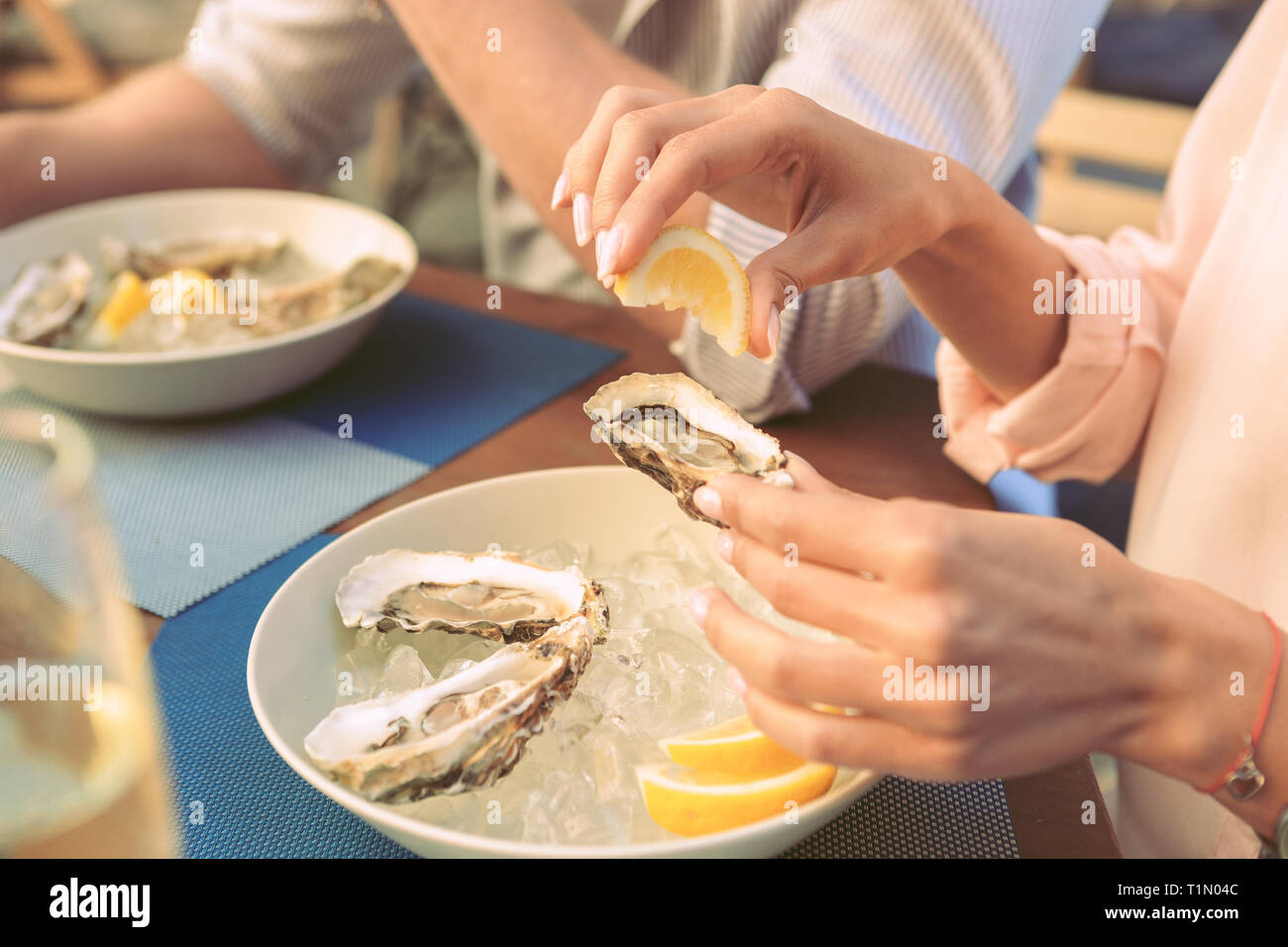 Woman with neat manicure squeezing lemon juice on fresh oyster Stock ...