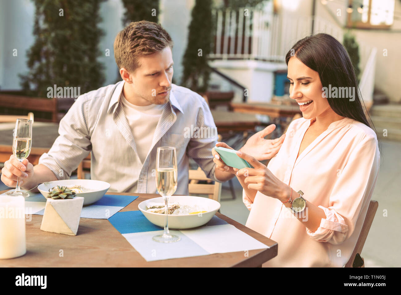 Cheerful long-haired woman making photo of her meal with smartphone ...