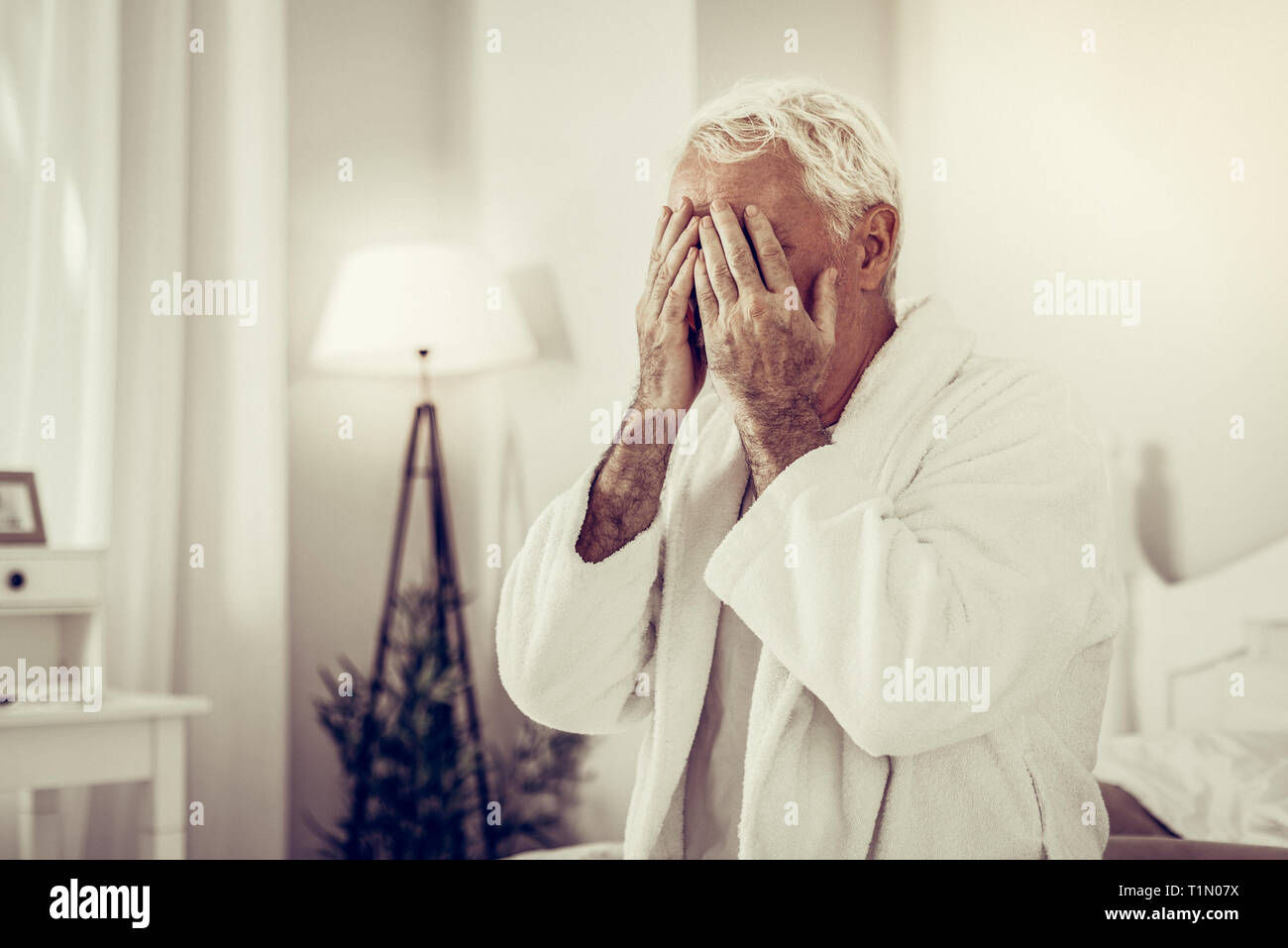 Portrait of sick aging white-haired male palming face at bedroom Stock ...