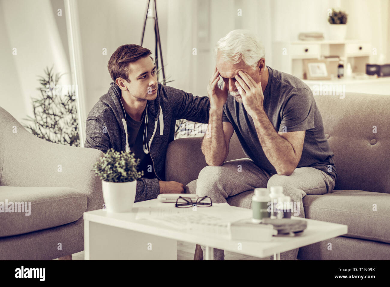 Young dark-haired pleasant son calming down aging silver-haired ...