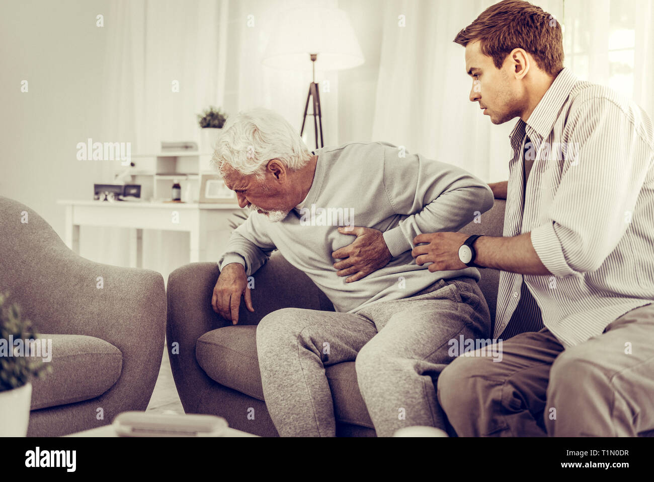 Shocked son trying to help father with a heart attack Stock Photo - Alamy