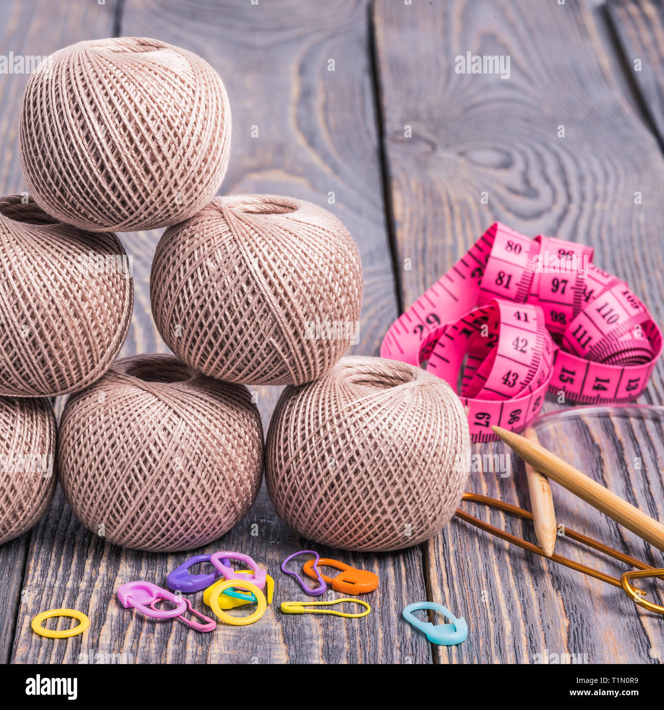 Balls of yarn, knitting needles, measuring tape and clips on wooden ...