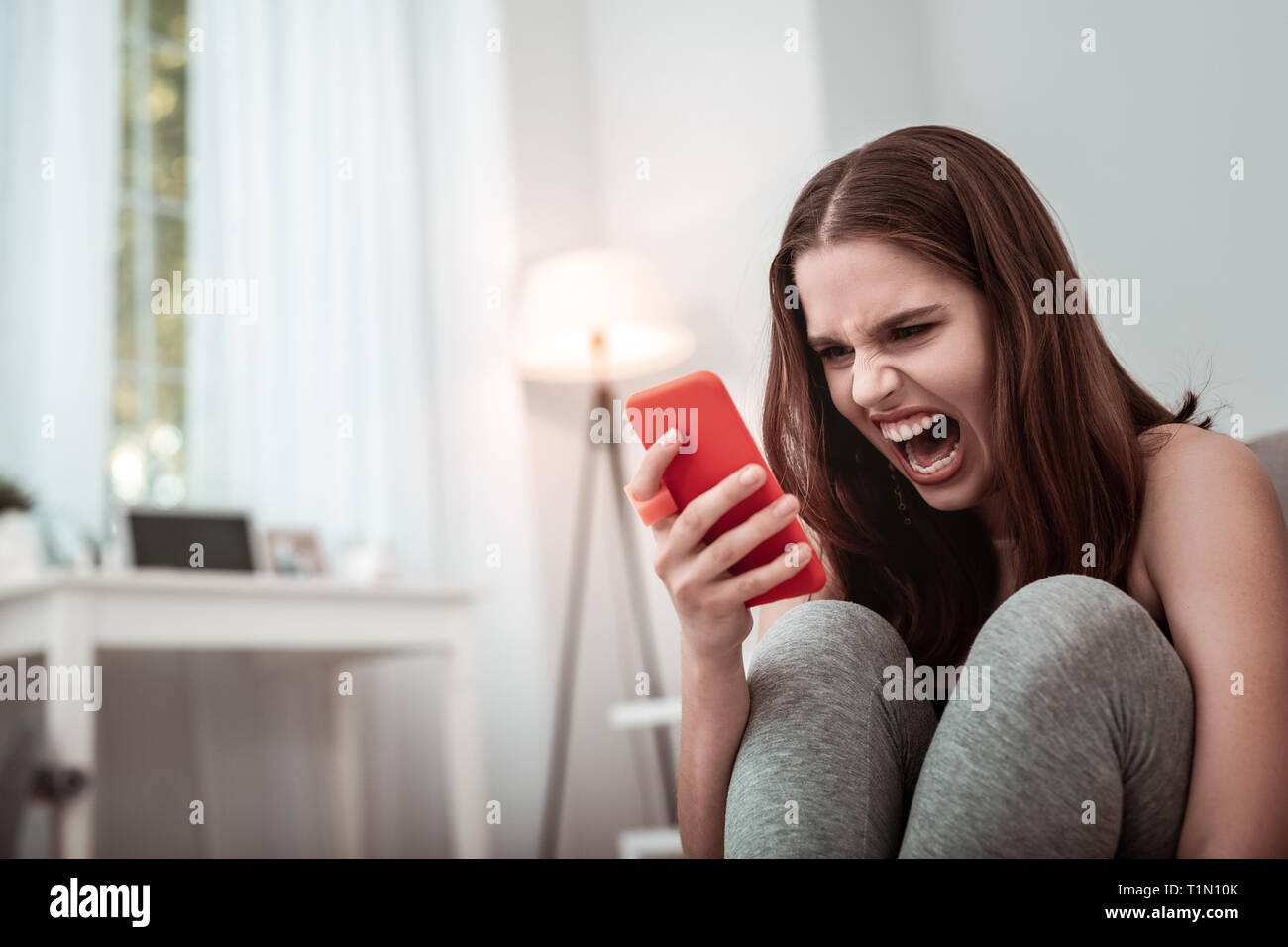 Stressed girl shouting at her smartphone while texting Stock Photo - Alamy