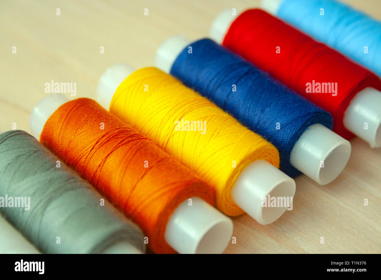 Many multi colored yarn strings bobbins on bright wooden background ...