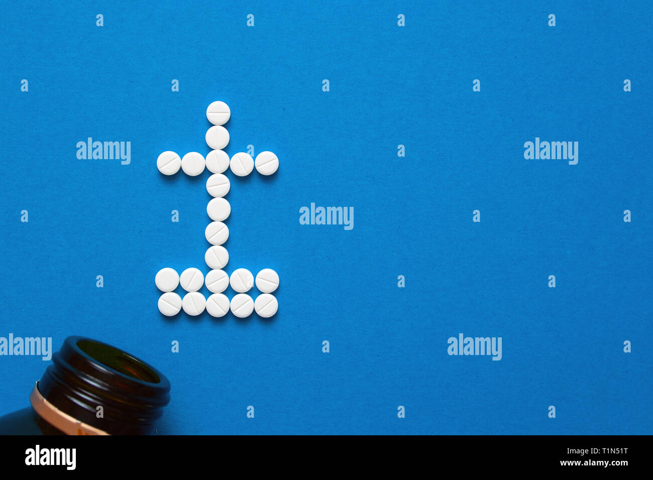 white pills in the shape of a grave cross are scattered on a blue ...