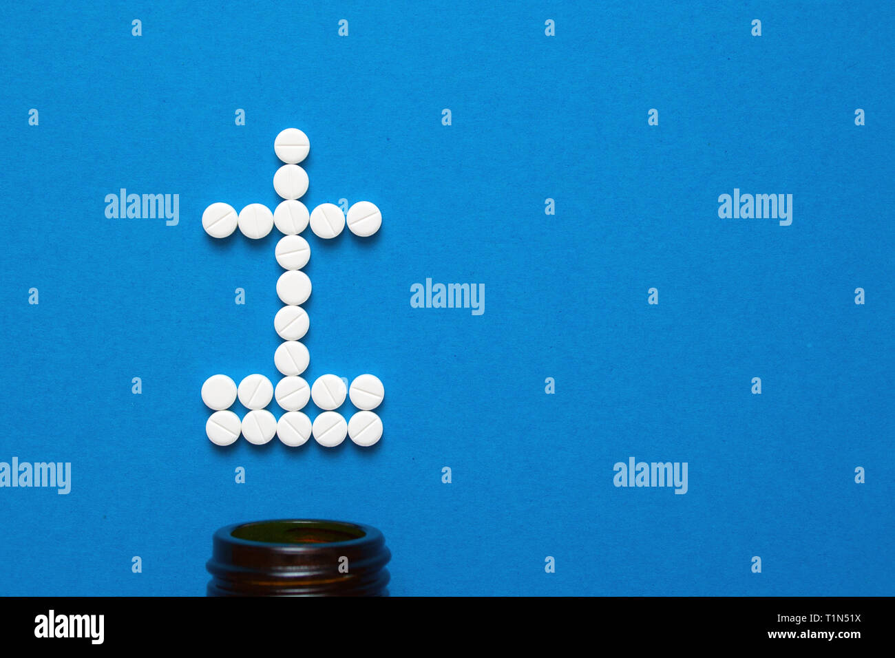 white pills in the shape of a grave cross are scattered on a blue ...