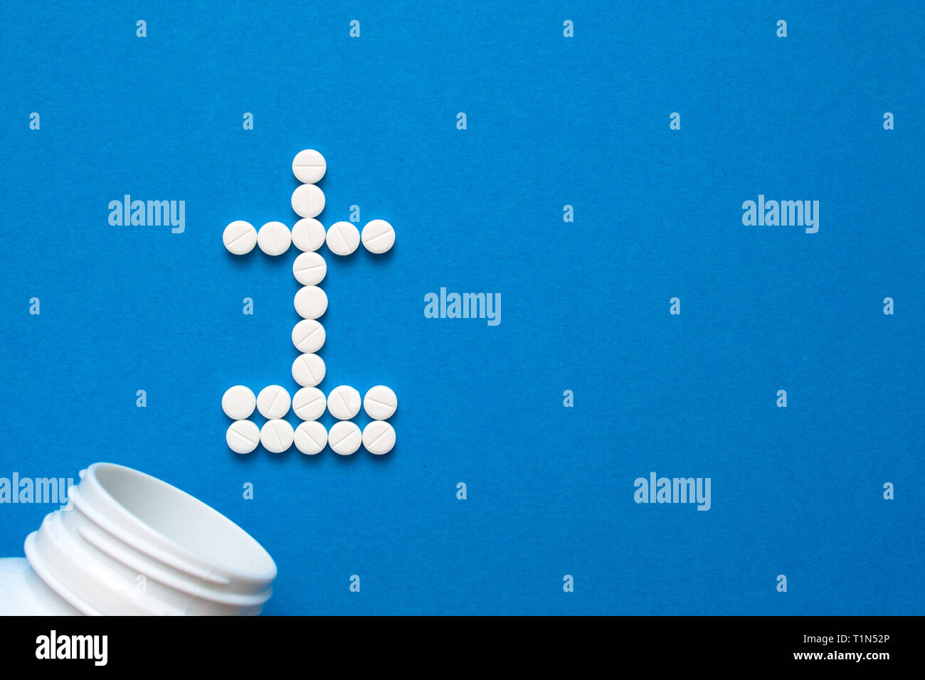 white pills in the shape of a grave cross are scattered on a blue ...