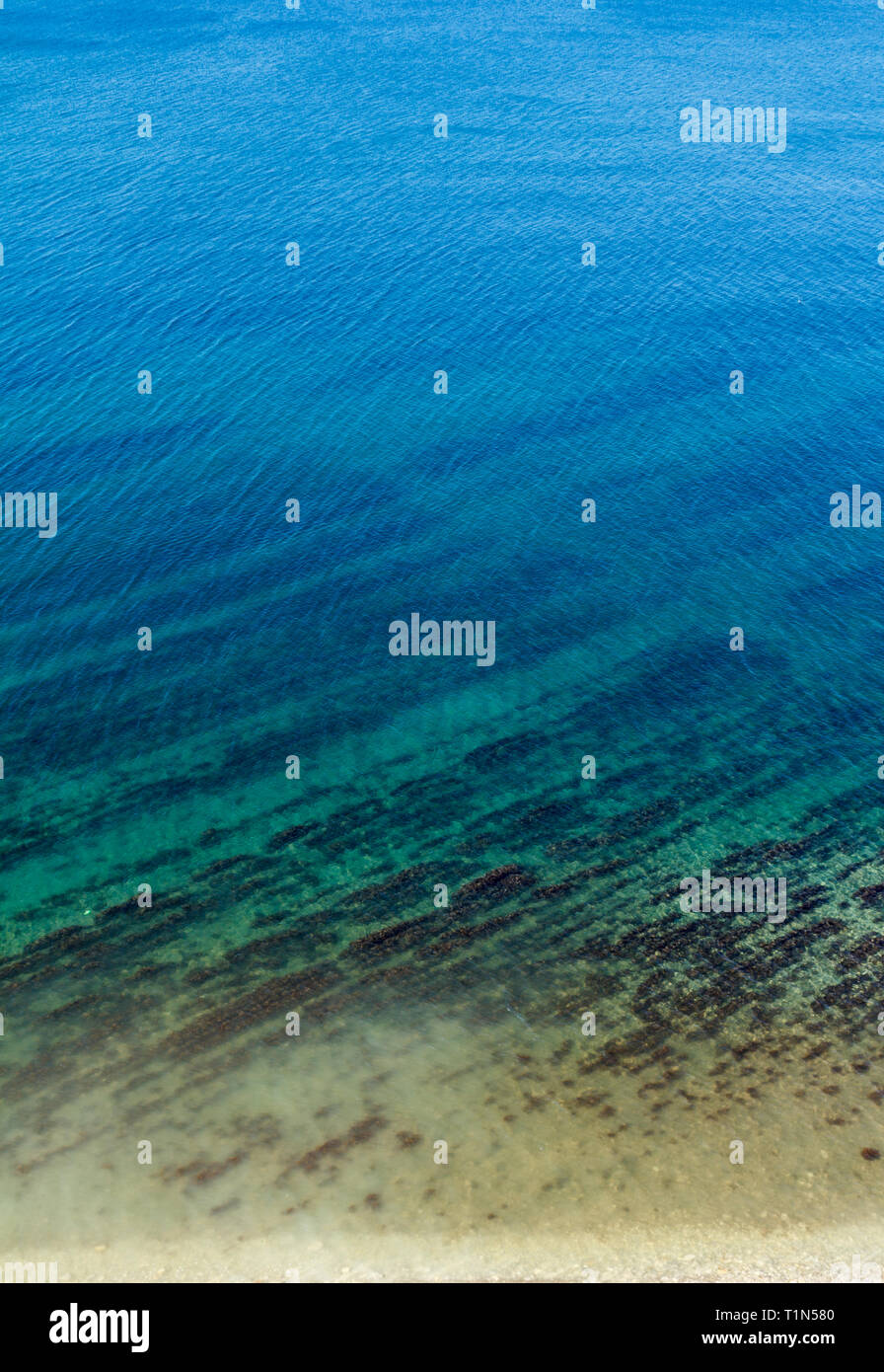 clean blue sea, with a pebbly-rocky beach Stock Photo - Alamy