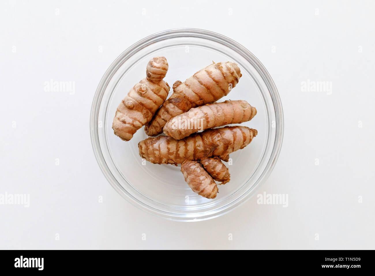 Turmeric, tuber, intact root. Single ingredient in glass bowl isolated ...