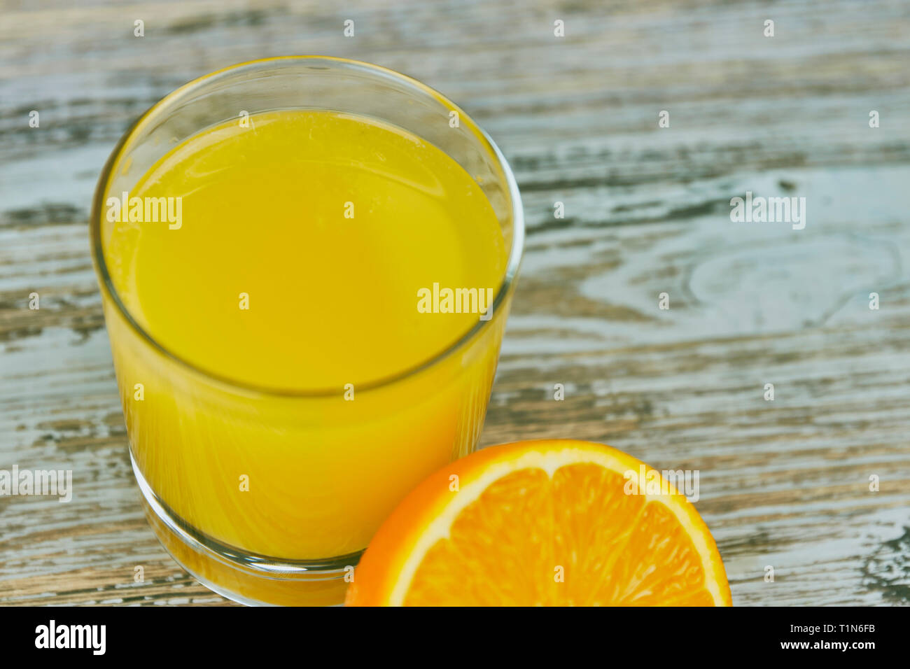 a glass of fresh orange juice with fresh citrus fruits on a light ...