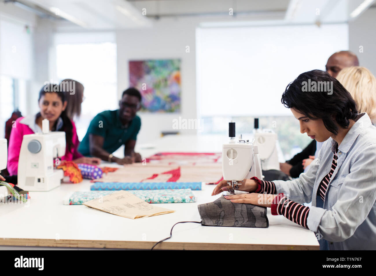 Fashion design students working at sewing machines in studio Stock ...