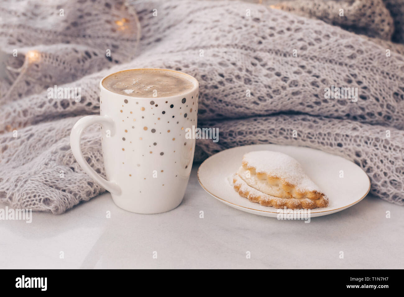 Stack of warm cozy knitwears and a cup of coffee on white marble ...