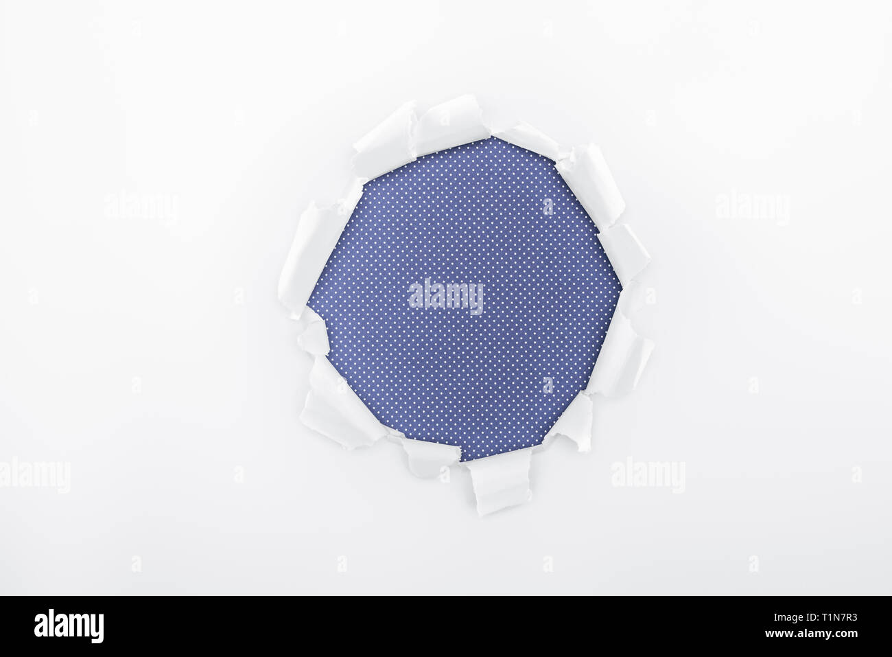 ripped hole in textured white paper on blue dotted background Stock ...