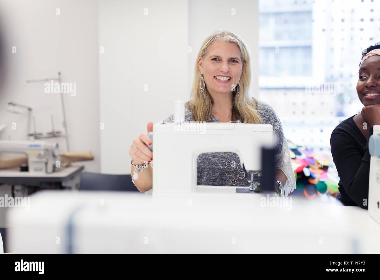 Portrait happy fashion designer working at sewing machine Stock Photo ...