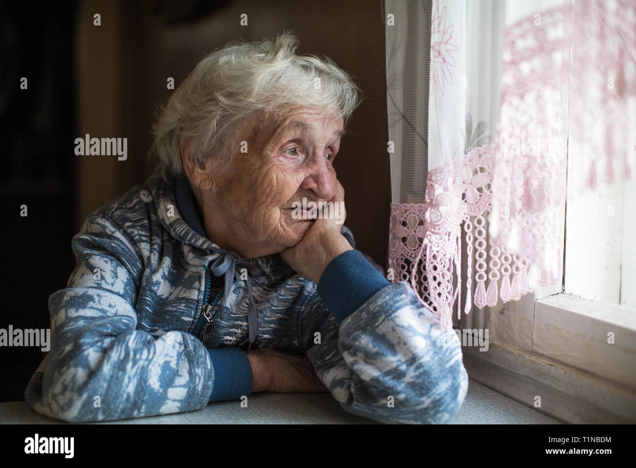 Elderly woman looks out the window Stock Photo - Alamy