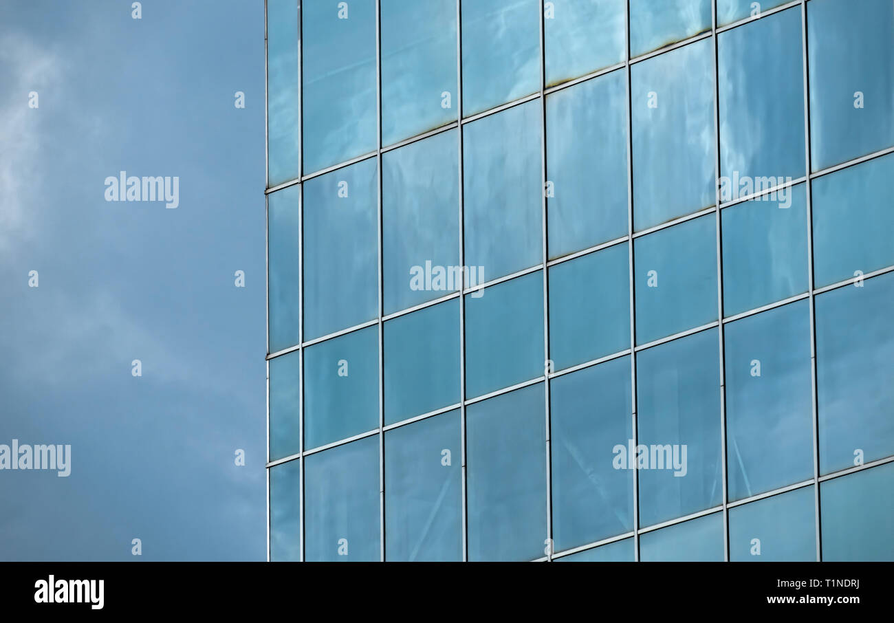 Skyscraper wall with the reflection of the cloudy sky in the windows ...