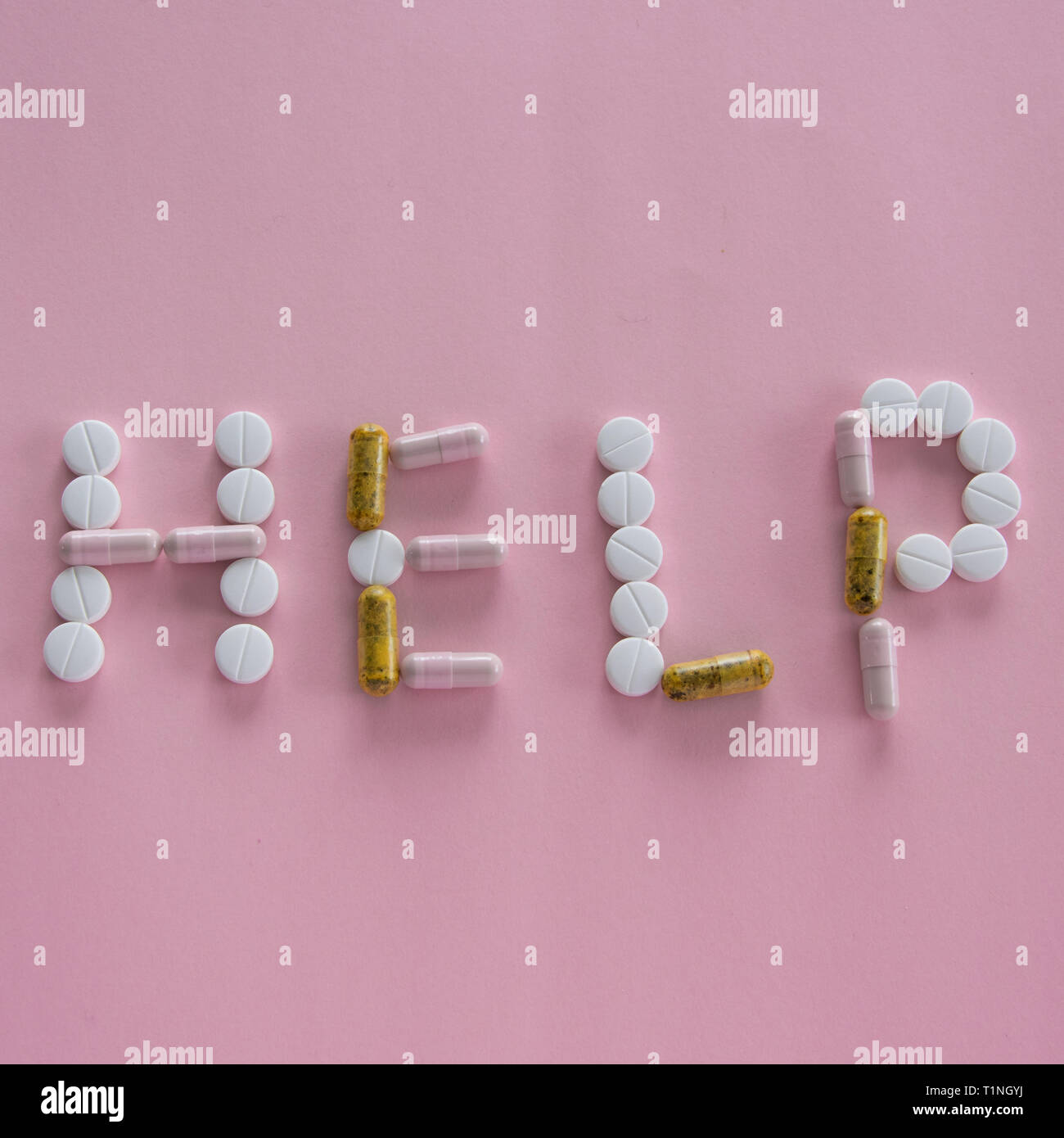 Different medication pills in HELP word shape on pink background ...