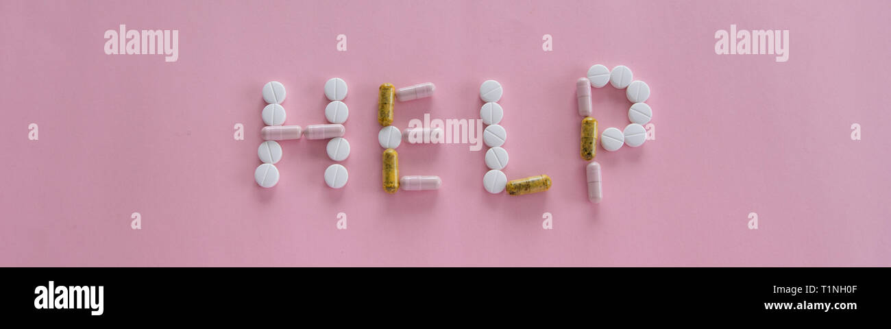 Different medication pills in HELP word shape on pink background ...