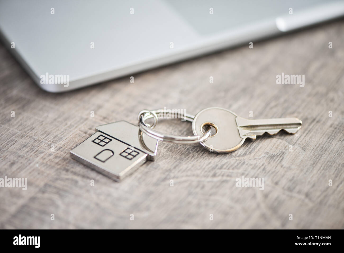 House keys on a house shaped keychain on wood background concept for ...