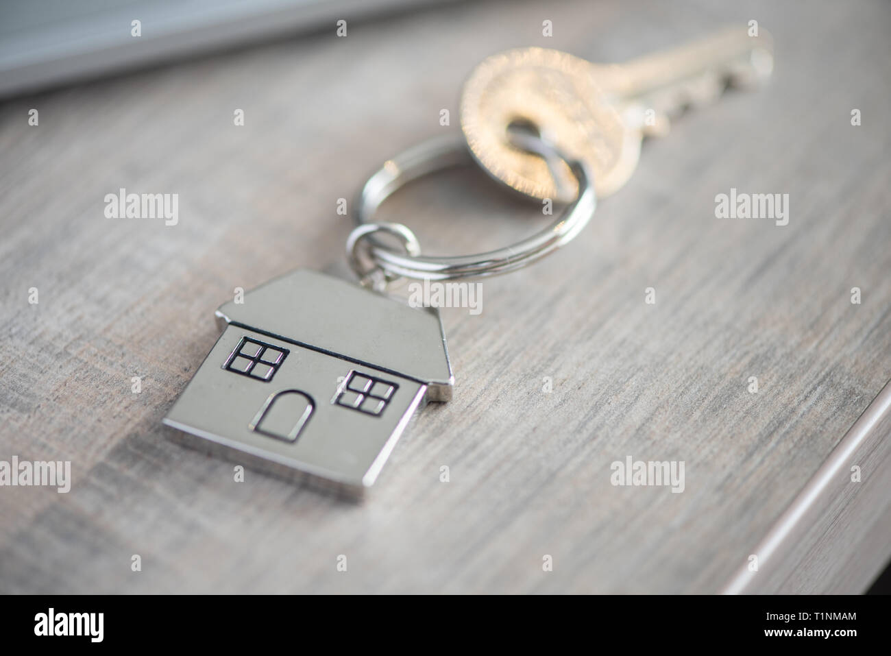 House keys on a house shaped keychain on wood background concept for ...
