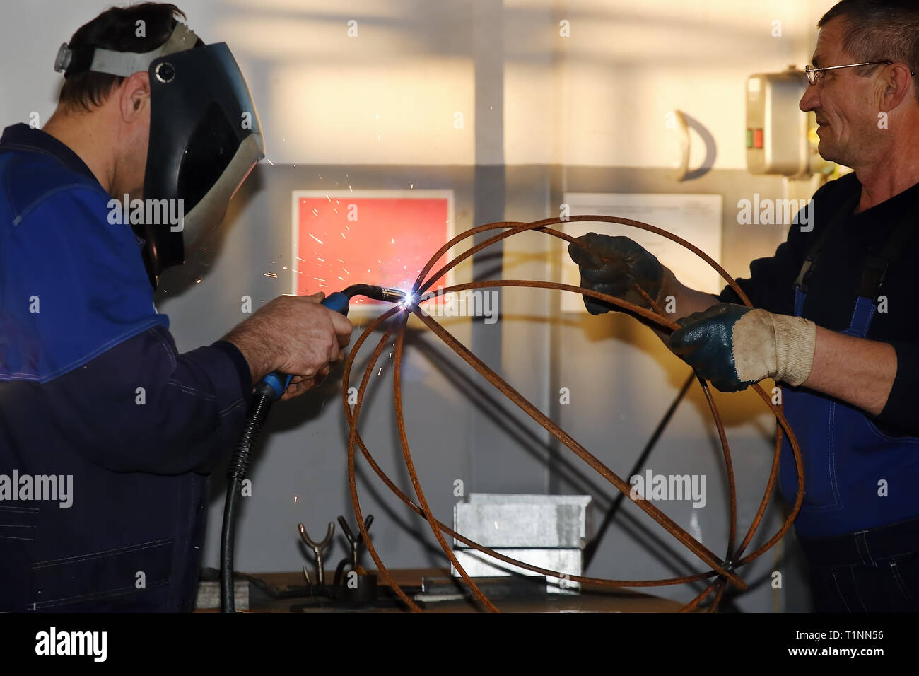 The welder and his assistant work together. Two white men in the ...