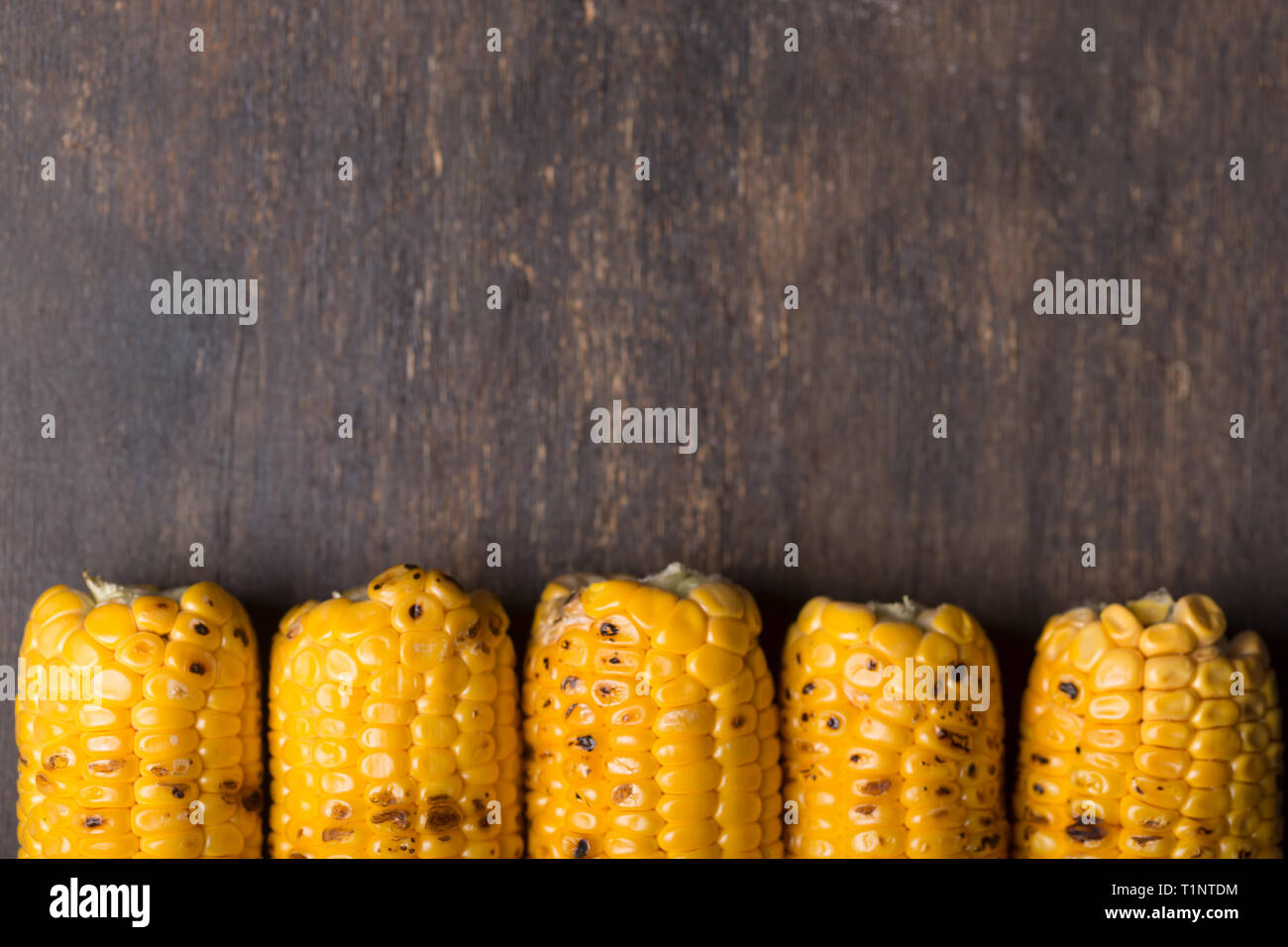 Grilled corn cobs on the brown rustic background with copy space. Close ...