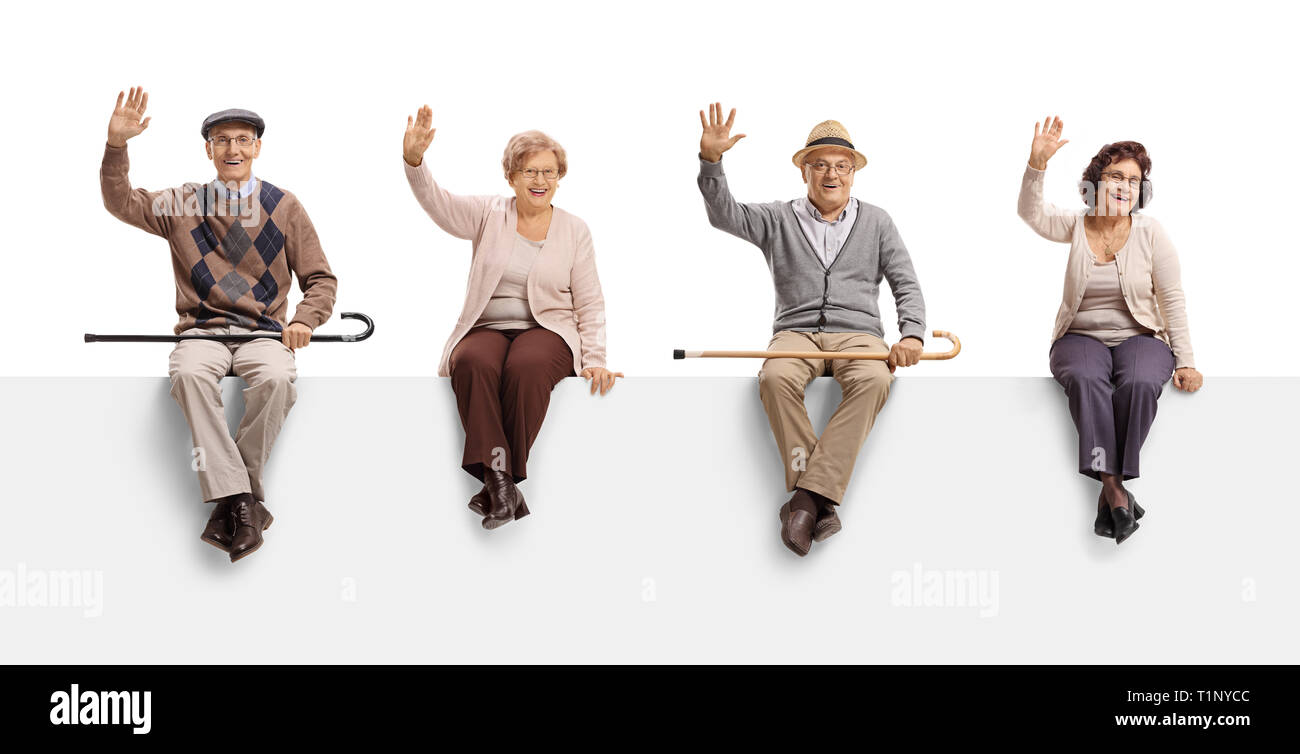 Senior men and women sitting on a blank billboard sign and waving at ...