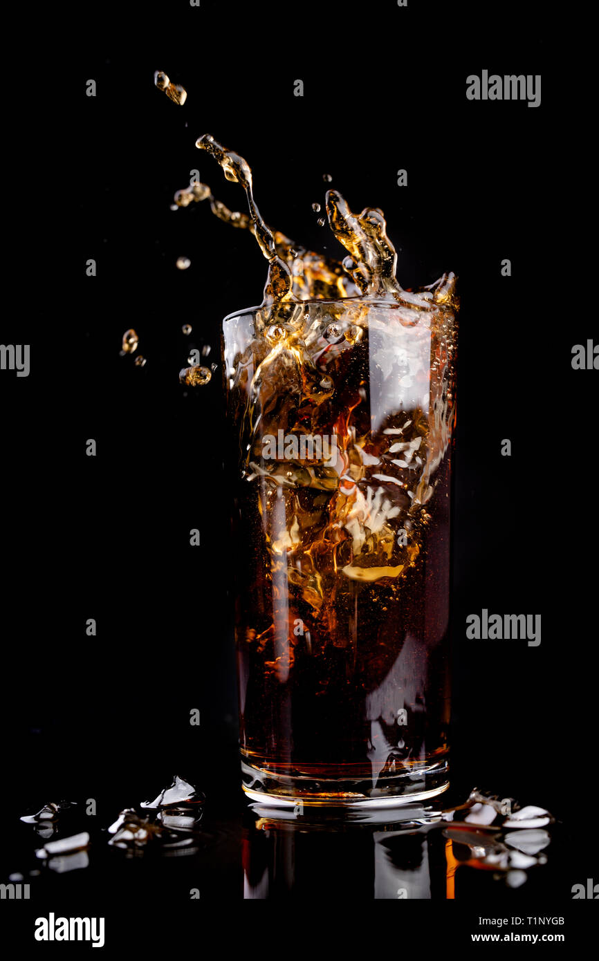 Dropping ice into a glass with a cold drink. Splash of drink in the bar ...