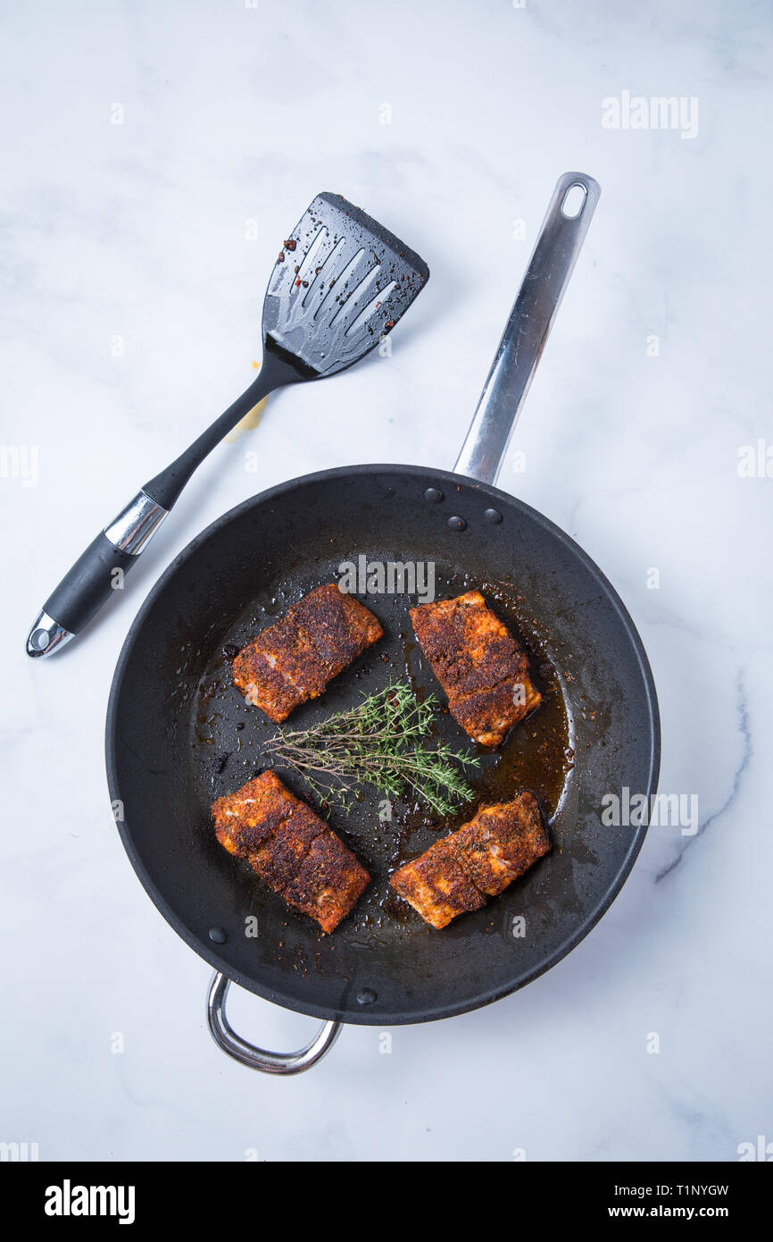 Pan-fried spicy fish in a frying pan with a spatula. Cooking fish ...