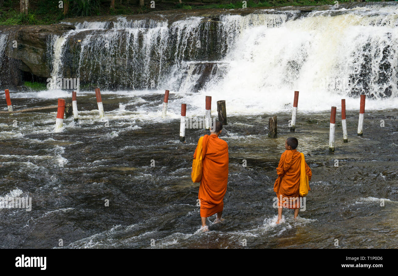Two young buddhist monks walking through shallow water towards a ...