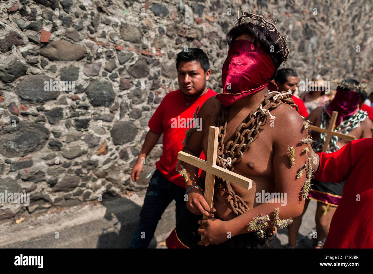 A hooded Catholic penitent, wearing chains and cactus spines stuck to ...