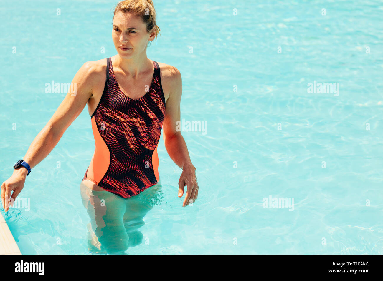 Young woman in swimsuit walking the wading pool. Female in swimwear in ...