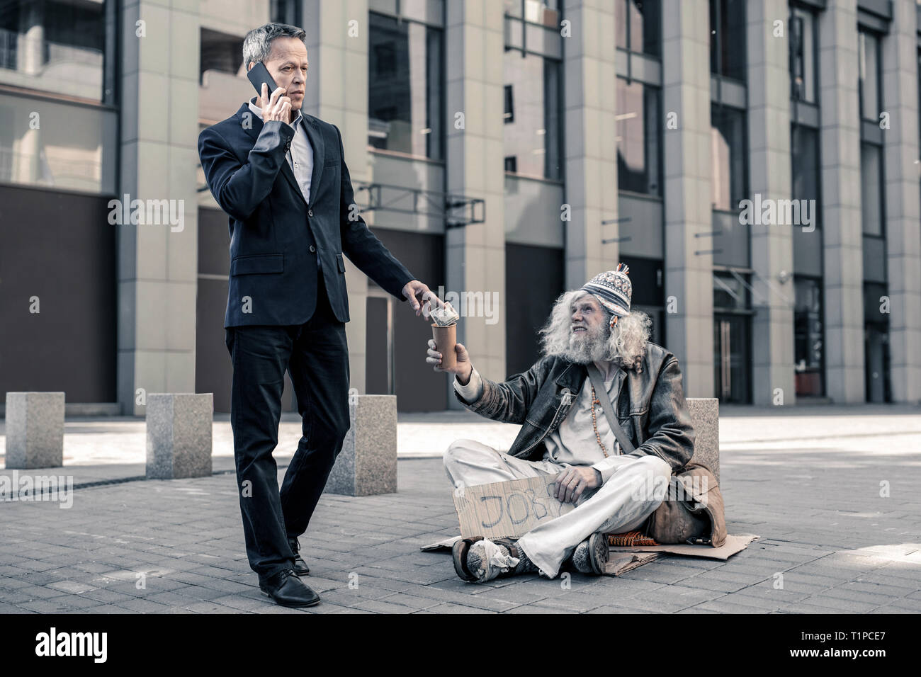 Thankful grey-haired senior homeless looking on business man Stock ...